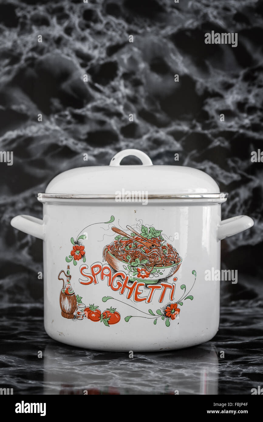 Big white vintage enamel saucepan with spaghetti design on black marble ...