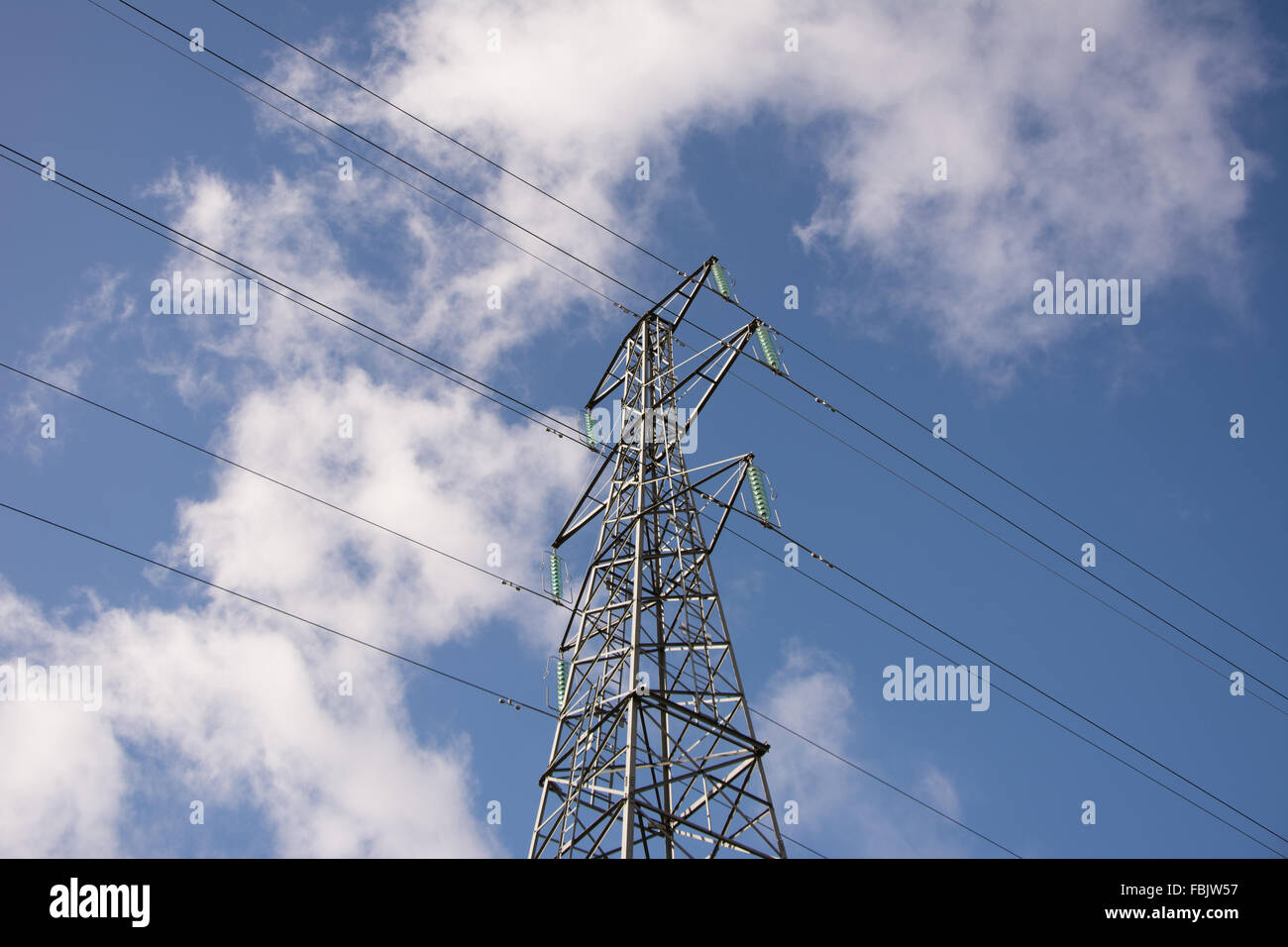 A large electricity pylon runs overhead beneath a blue sky Stock Photo ...