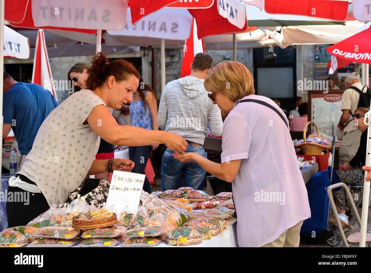 A woman selling local produce sweets at a stall in an open market in ...