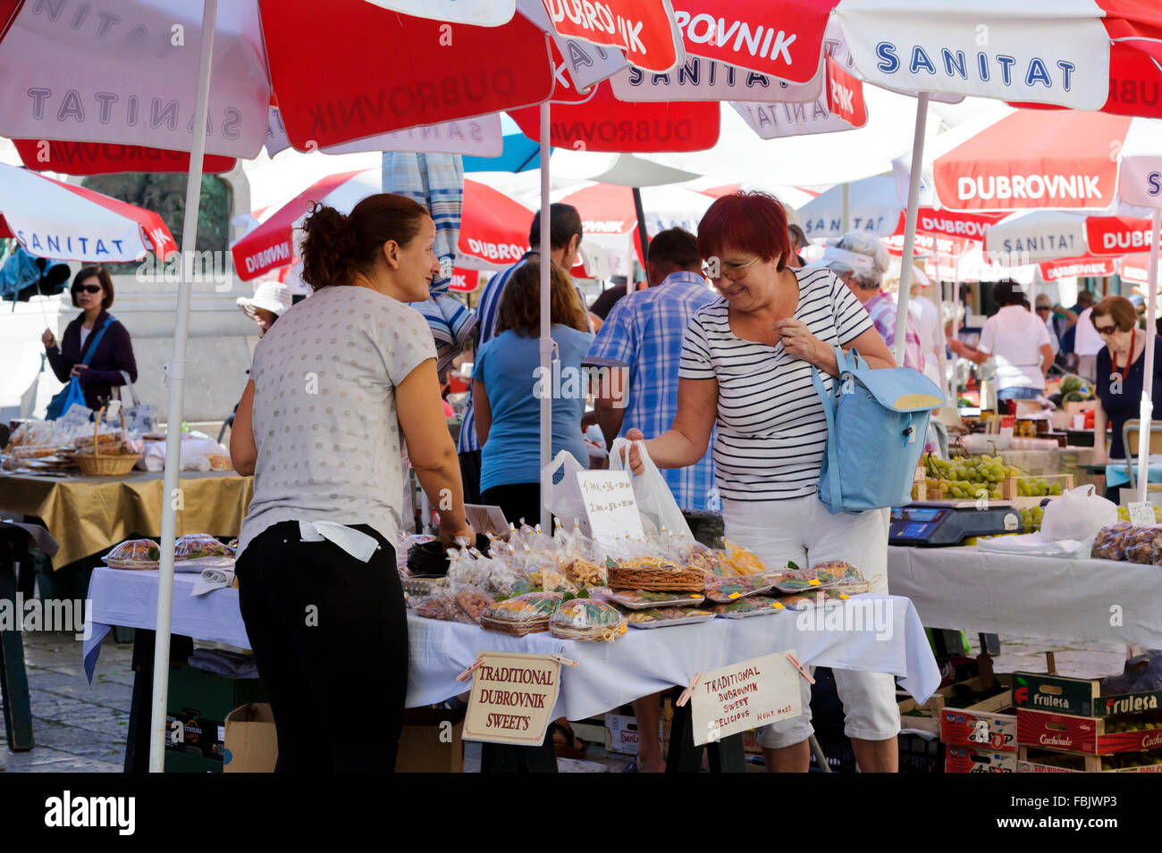 A woman selling local produce sweets at a stall in an open market in ...
