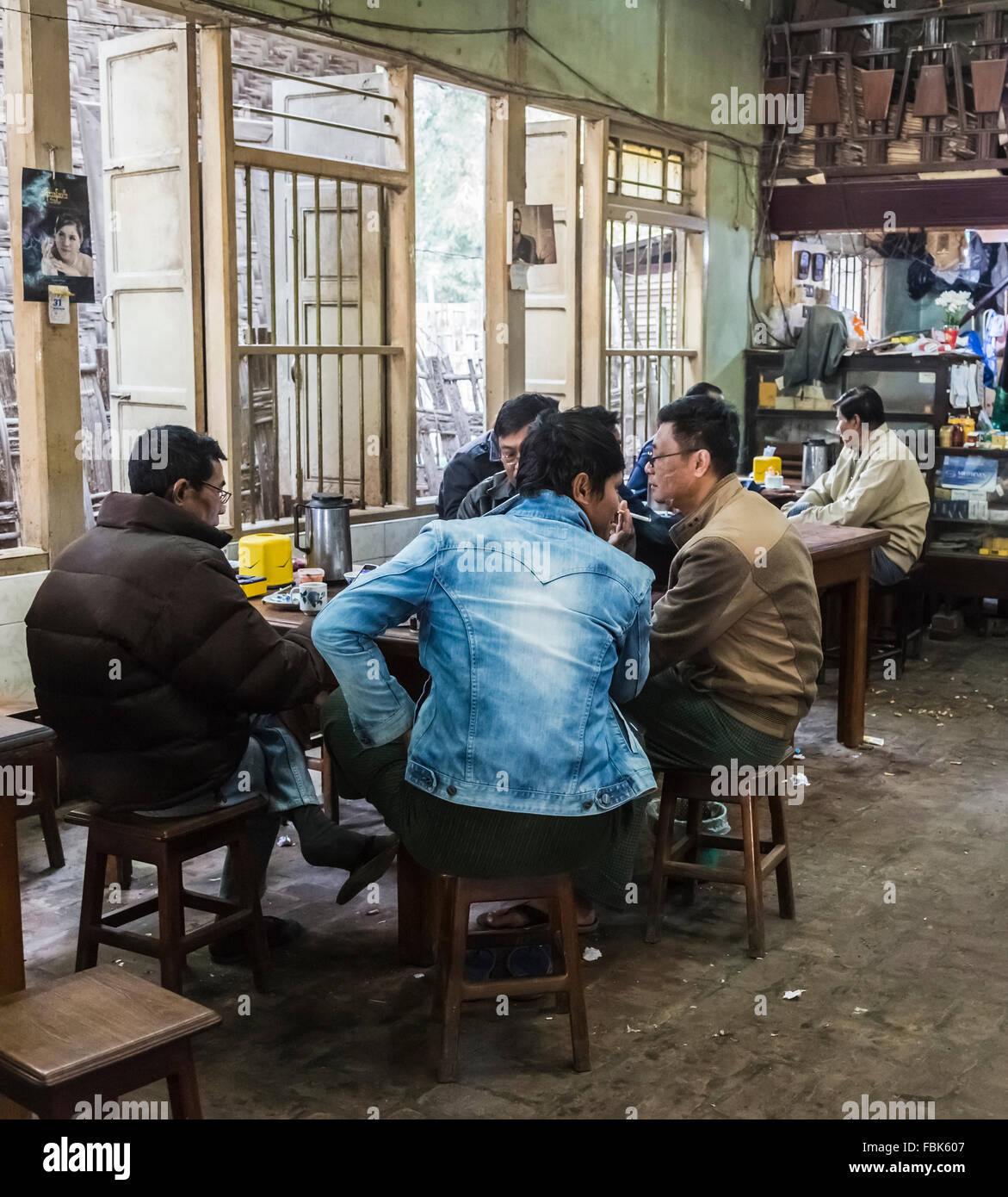 Interior of typical local cafe, local Burmese men sat around a table ...