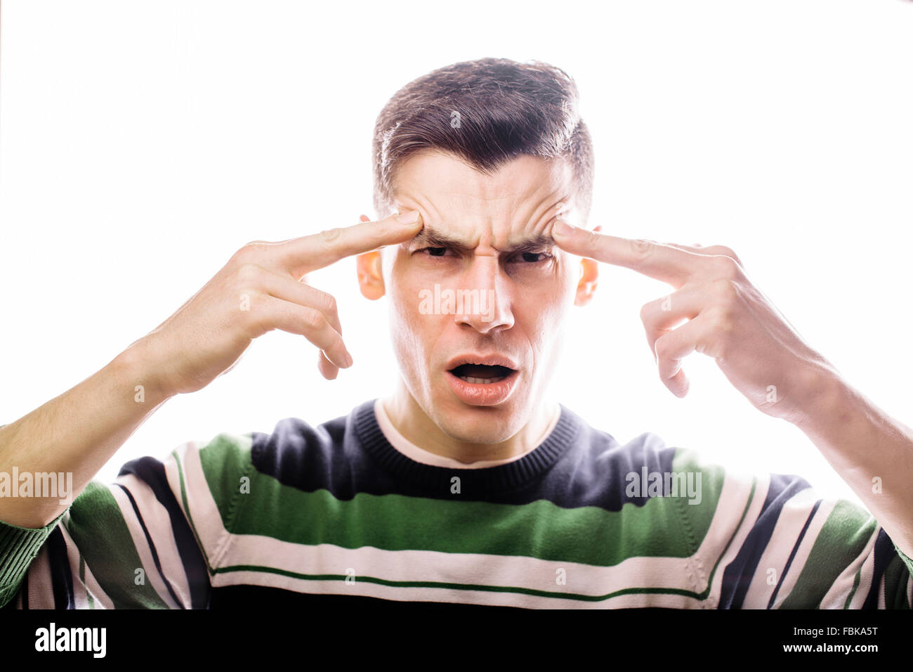Portrait of a smart serious young man standing against white background ...