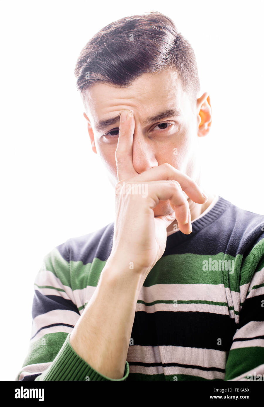 Portrait of a smart serious young man standing against white background ...