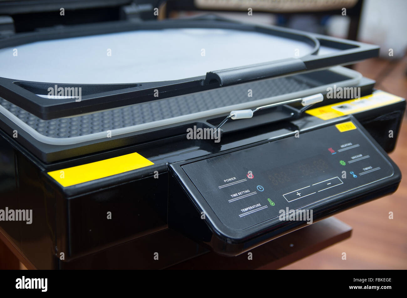 Black print screen machine on wooden desk with control panel visible ...