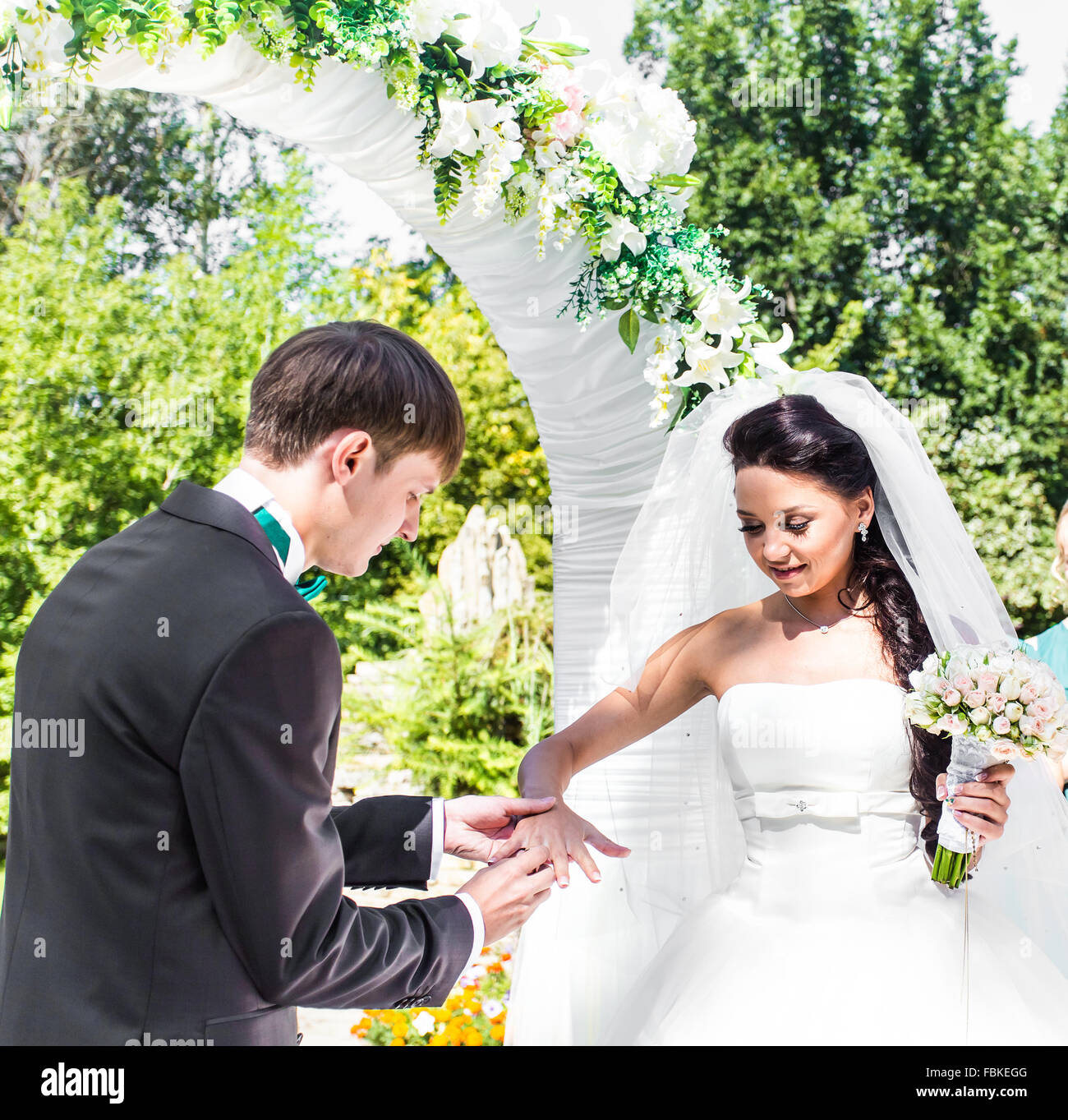 Groom putting a wedding ring on bride's finger Stock Photo - Alamy