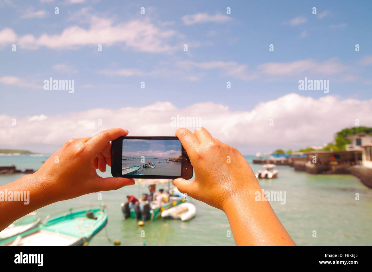 Hands holding mobile phone taking picture of beautiful island bay area ...
