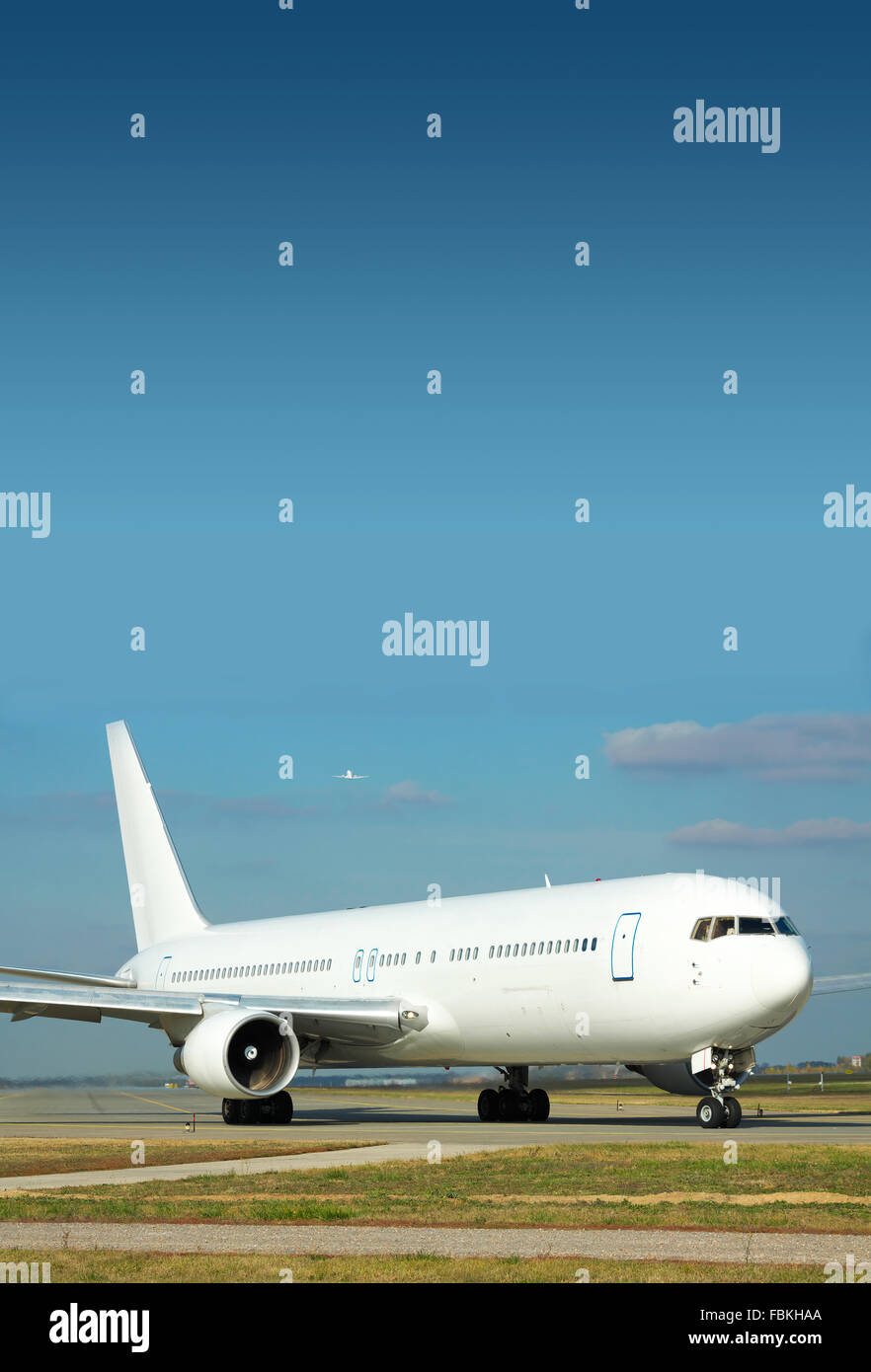 Passenger plane on the runway and another jet is taking off on the ...