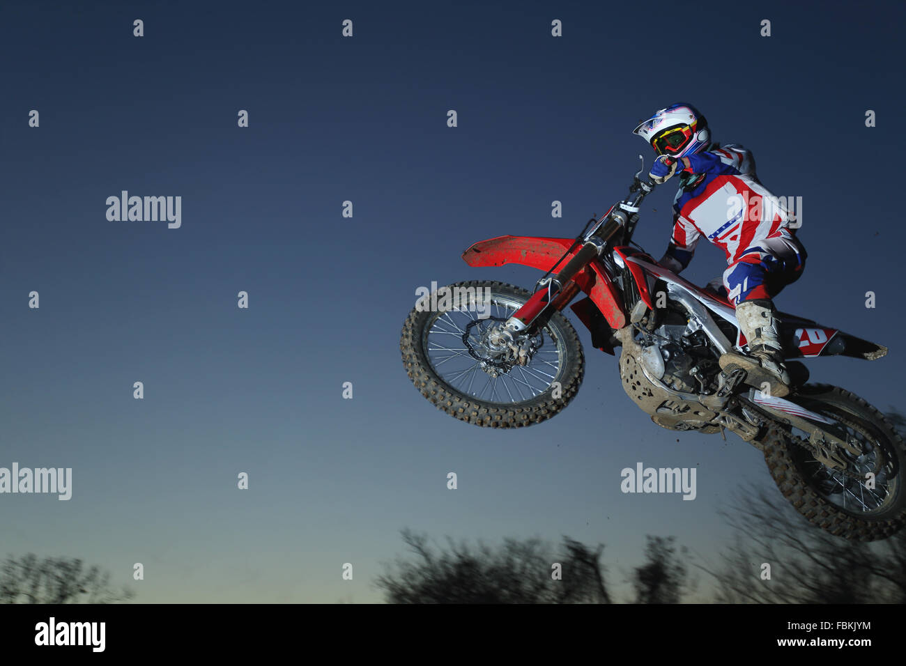Motocross biker jumping over dirt track Stock Photo - Alamy