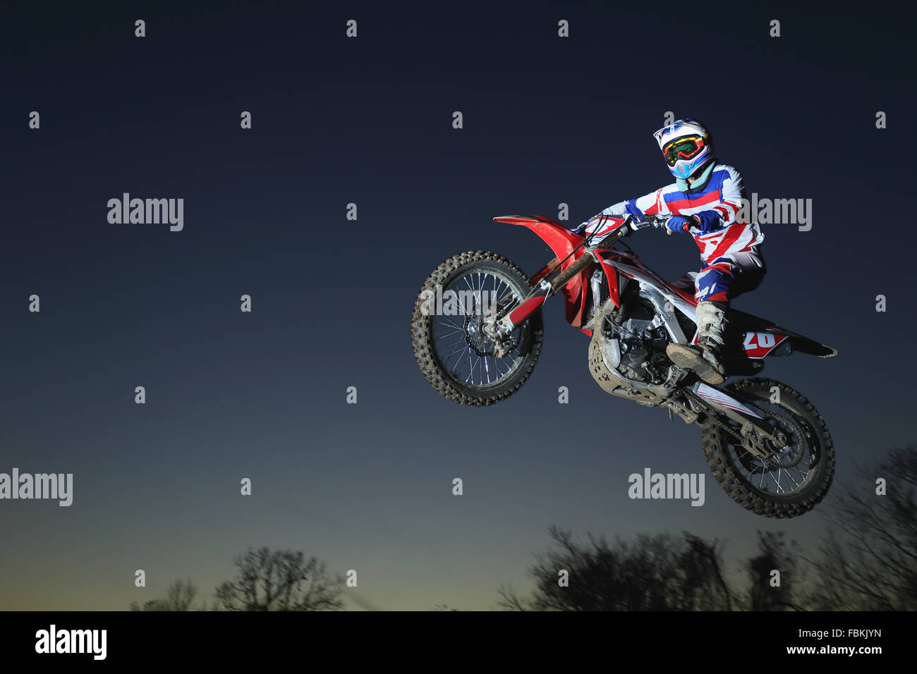 Motocross biker jumping over dirt track Stock Photo - Alamy