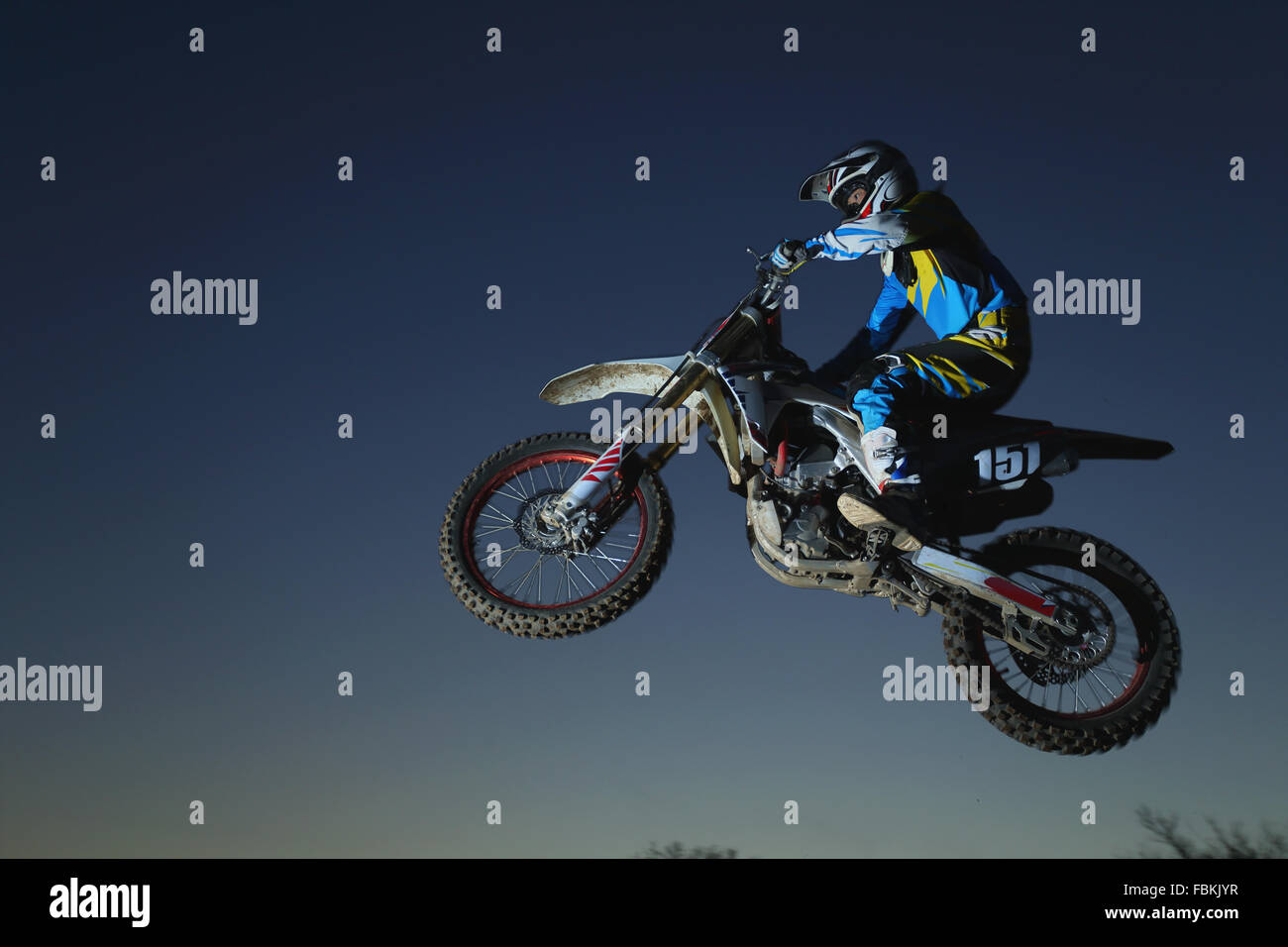 Motocross biker jumping over dirt track Stock Photo - Alamy