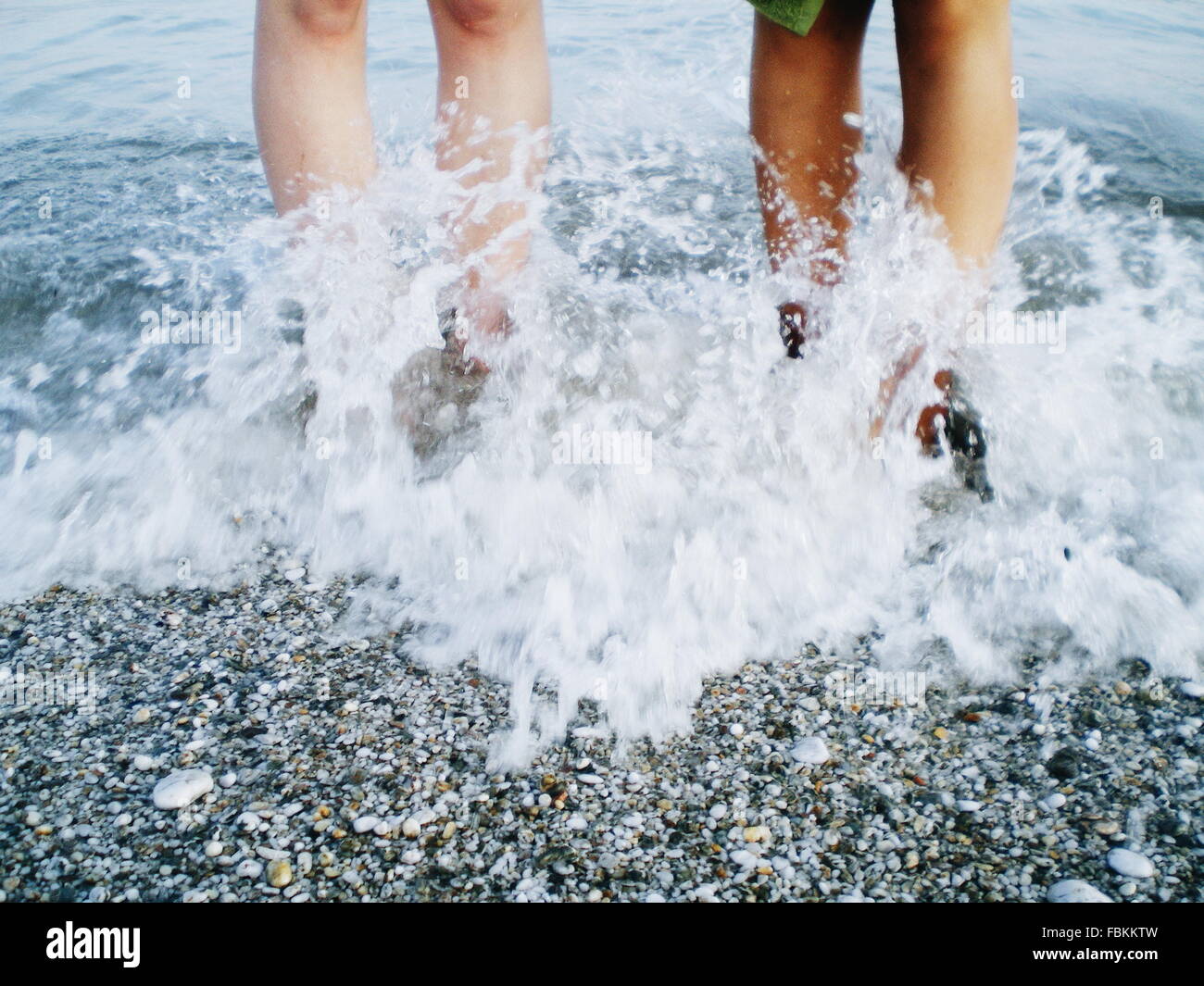 Two young women standing in the ocean splashing wave carefree spirit ...