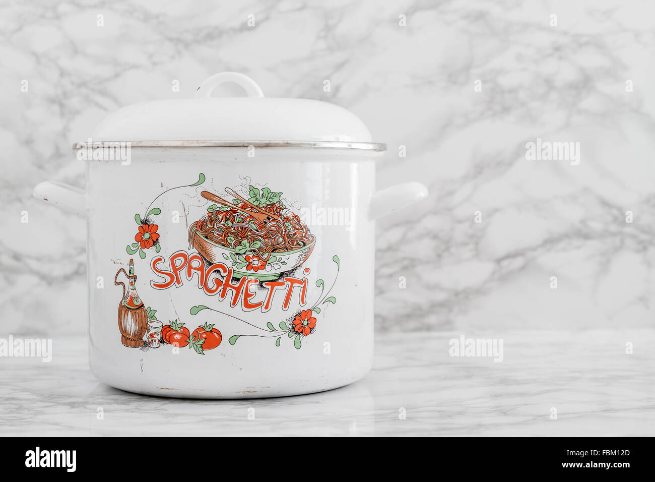 Big white vintage enamel saucepan with spaghetti design on white marble ...