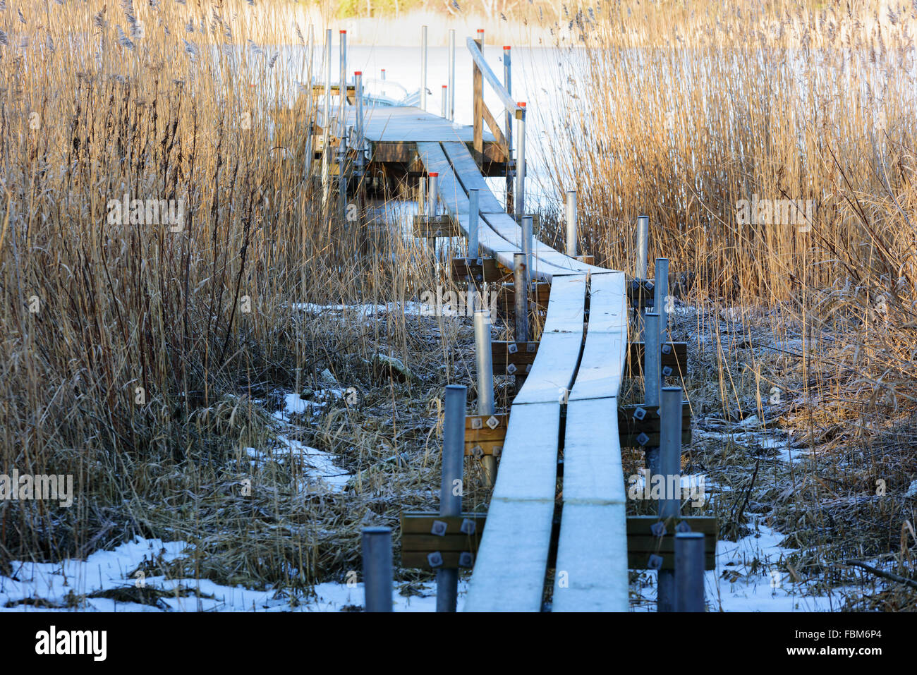 A long footbridge towards a pier is covered in frost and surrounded by ...