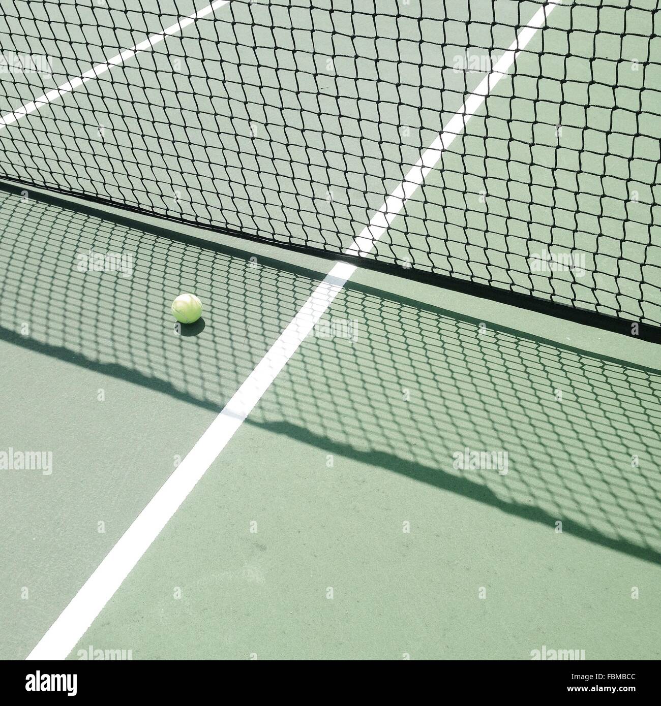 Tennis ball on tennis court in shadow of net Stock Photo - Alamy