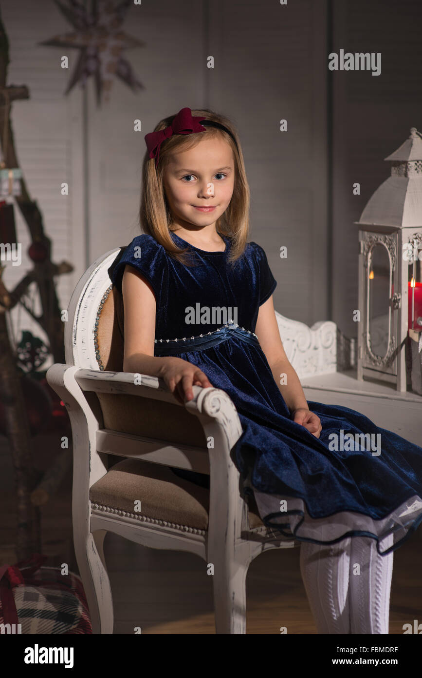 Girl in a party dress sitting in a chair Stock Photo - Alamy