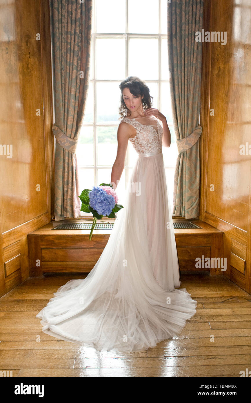 Woman in wedding dress in front of window Stock Photo - Alamy