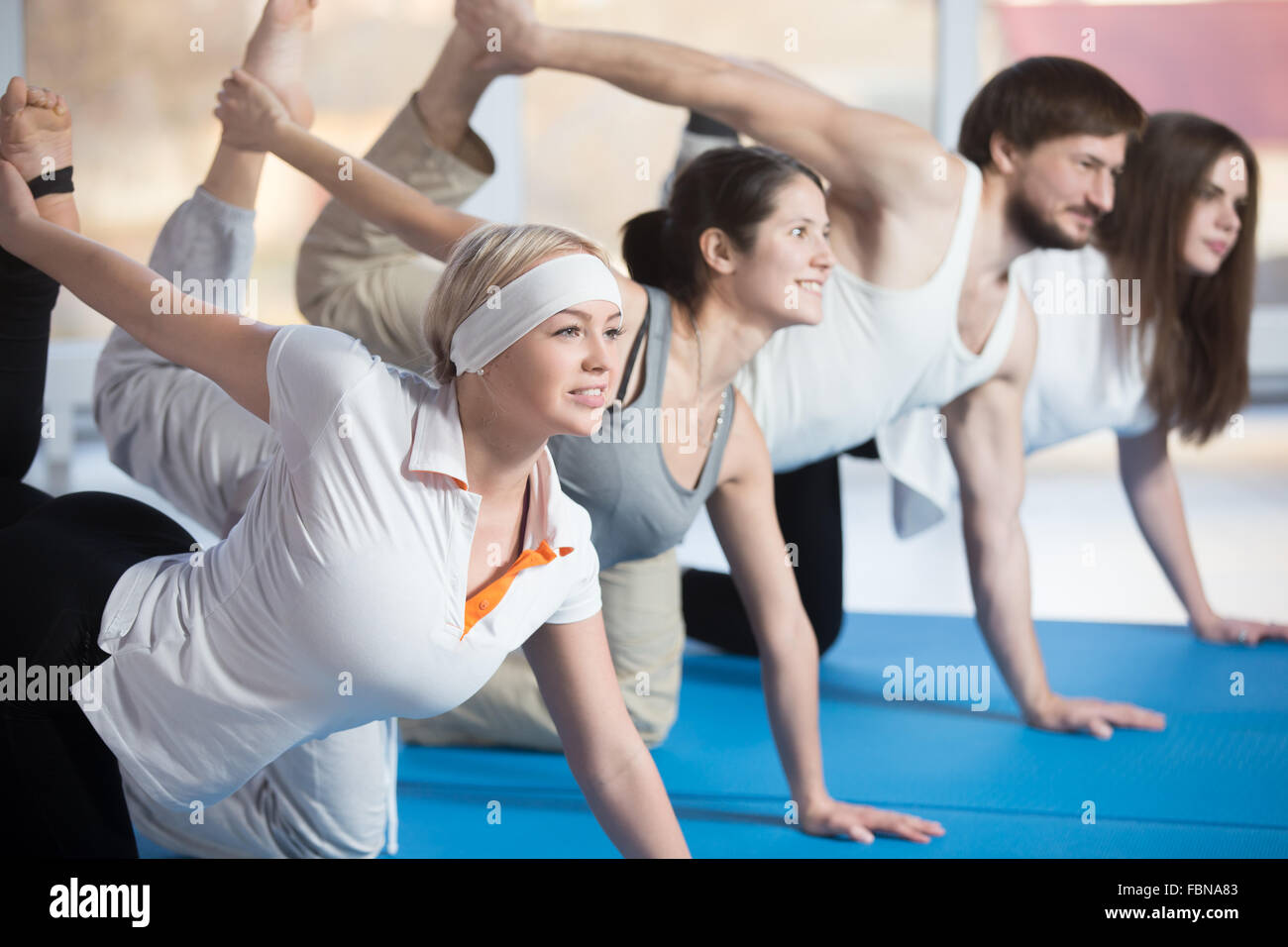 Fitness, stretching practice, group of four attractive smiling fit ...