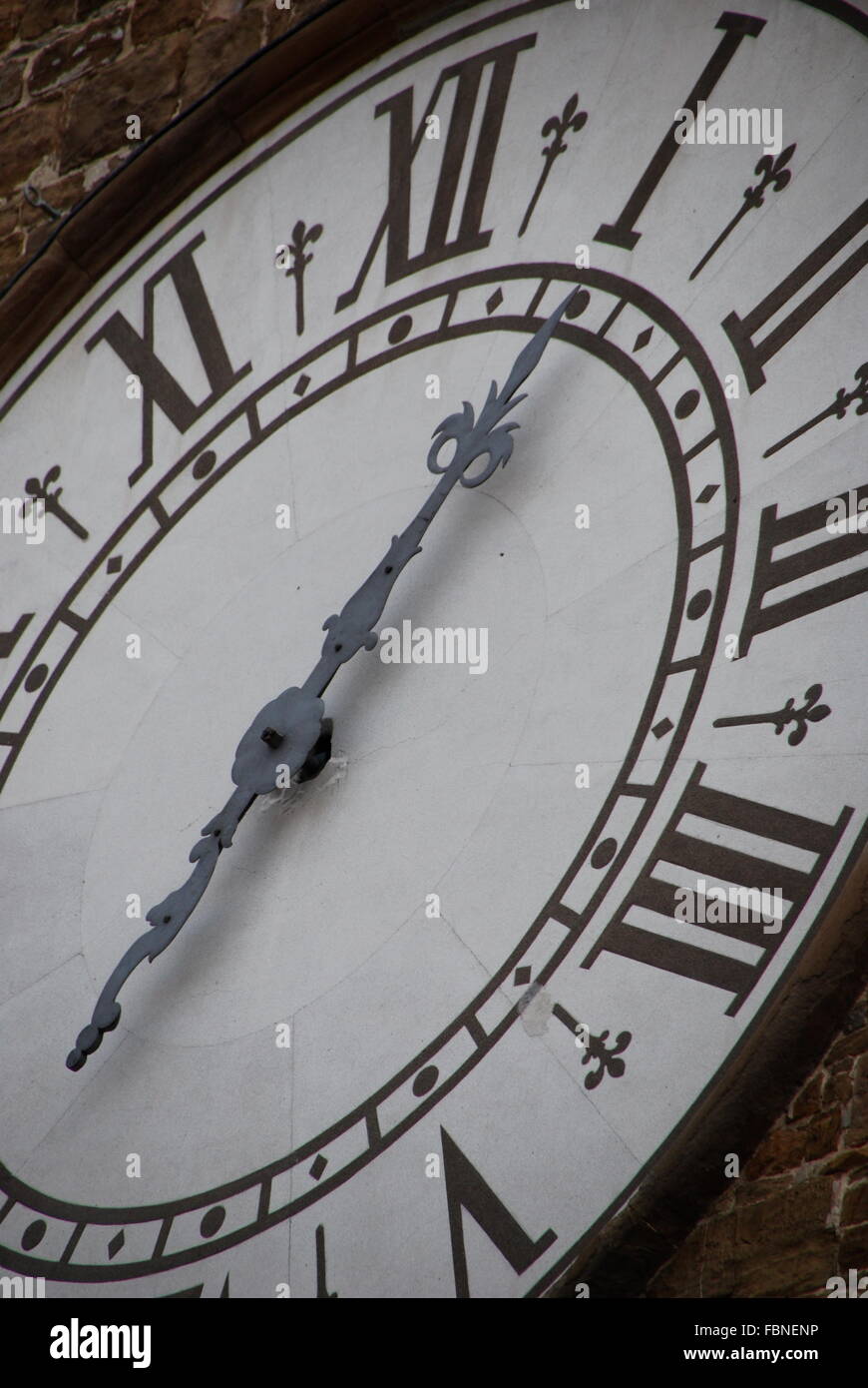 Old fashion tower clock with roman numbers and with arrow pointing to ...