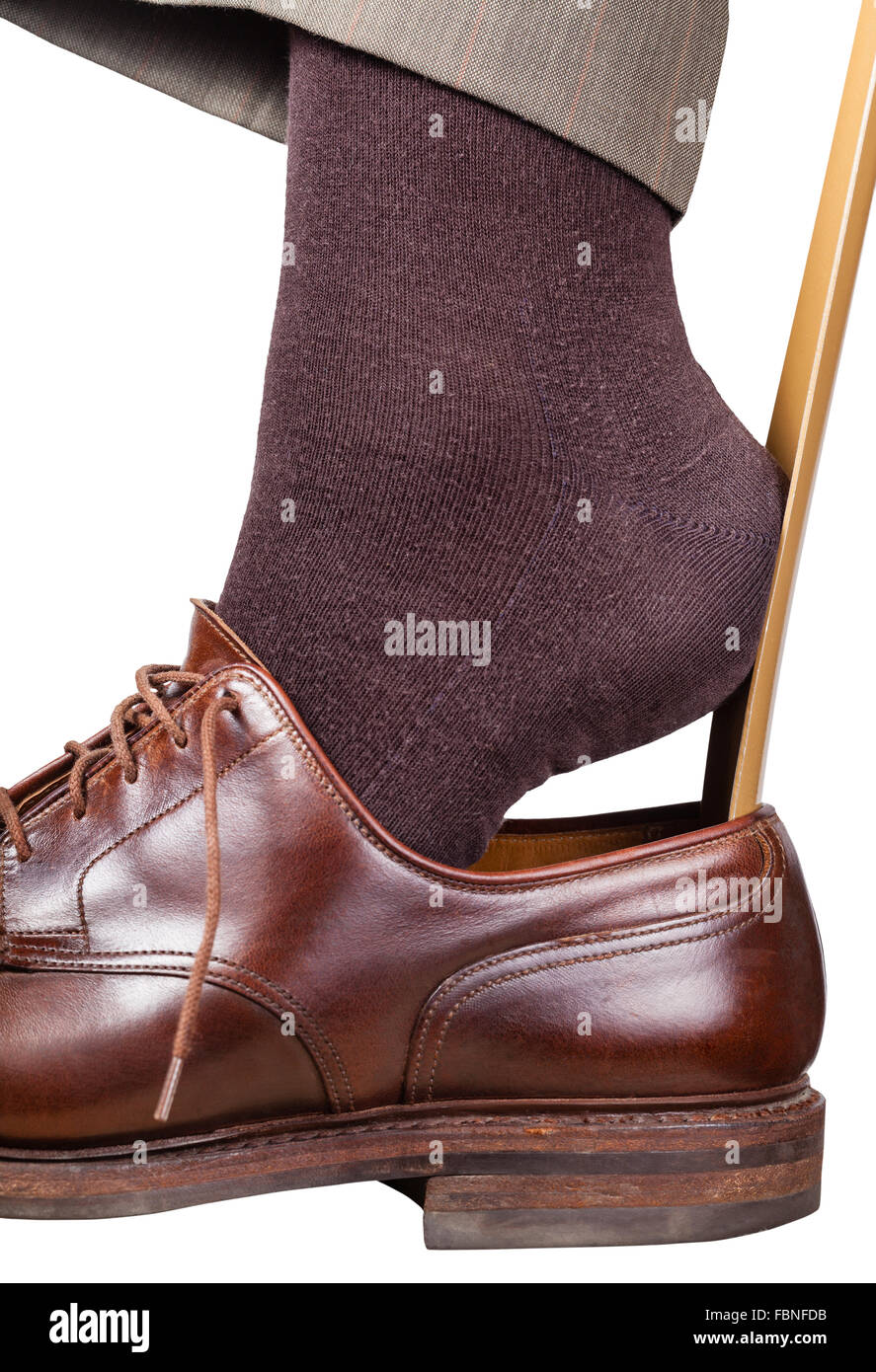 man puts on brown shoe with shoehorn isolated on white background Stock ...
