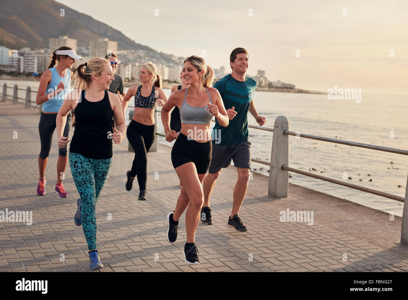 Portrait of young runners enjoying workout on the sea front path along ...