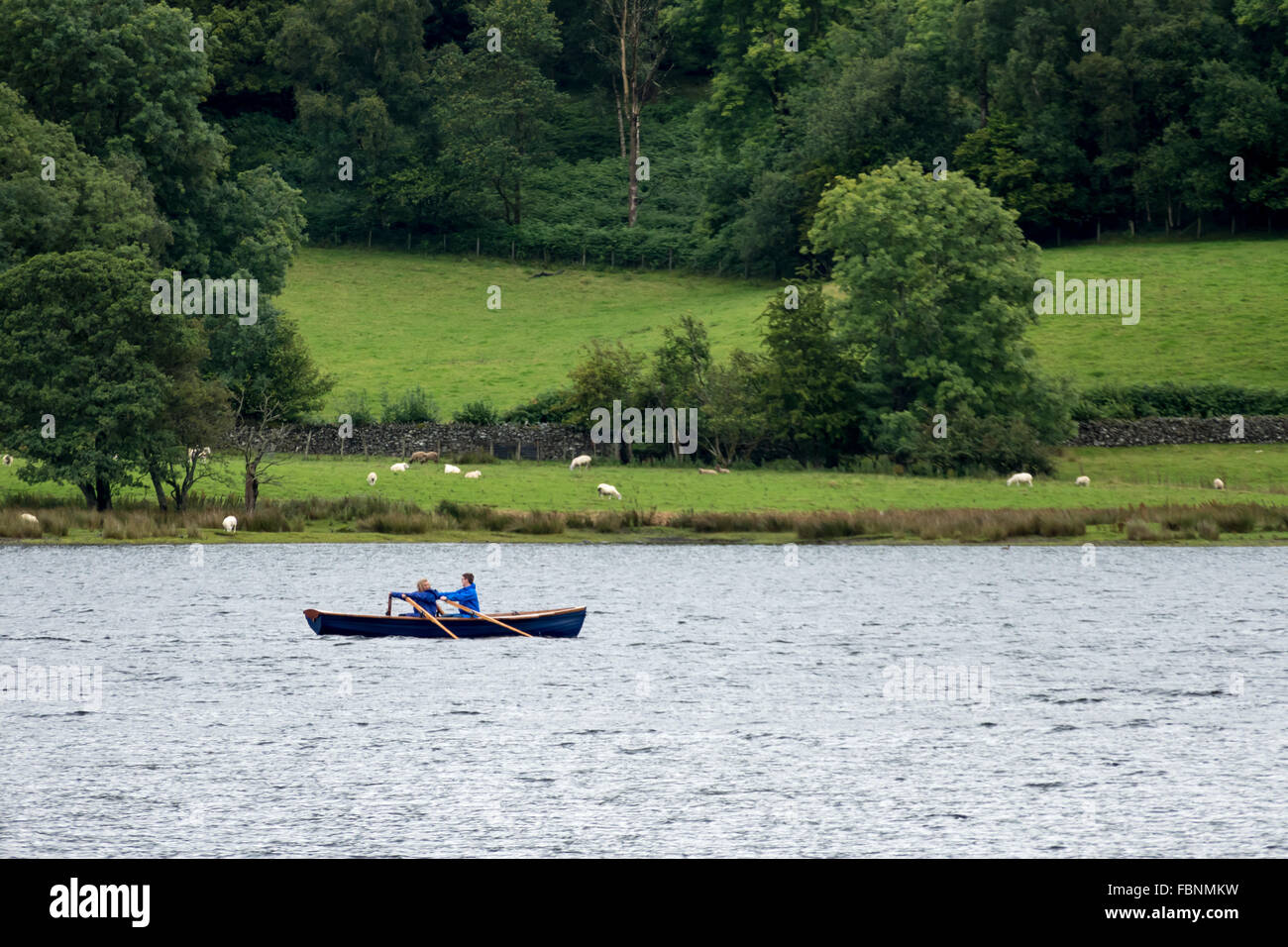 Two people in a rowing boat on Coniston Water Stock Photo - Alamy