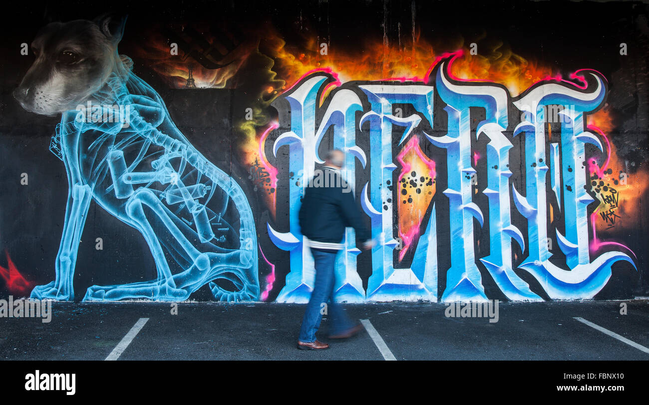 Pedestrian walking past street art, graffiti wall painting, decoration ...