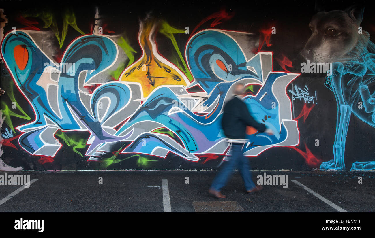 Pedestrian walking past street art, graffiti wall painting, decoration ...