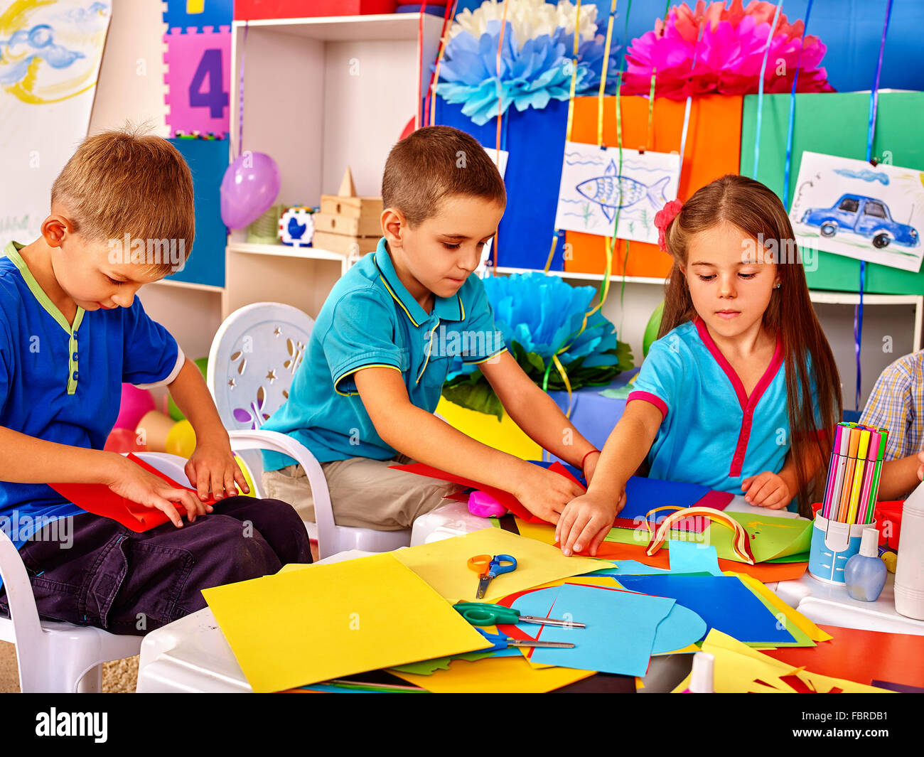 Kids holding colored paper on table in kindergarten Stock Photo - Alamy