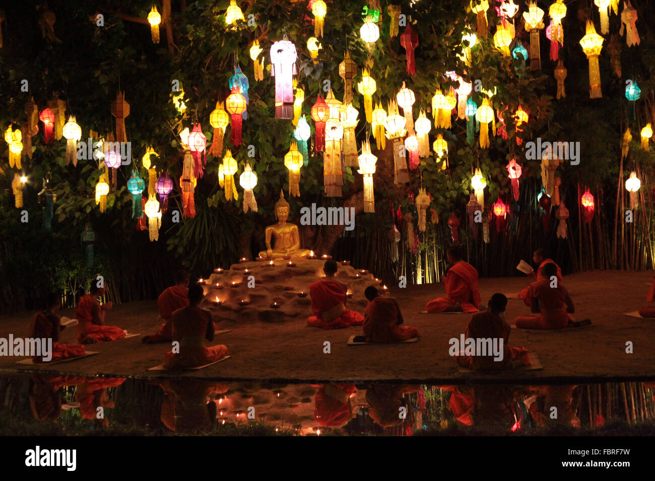Chiang Mai, Thailand, 2016. Monks in saffron robes sitting under tree ...