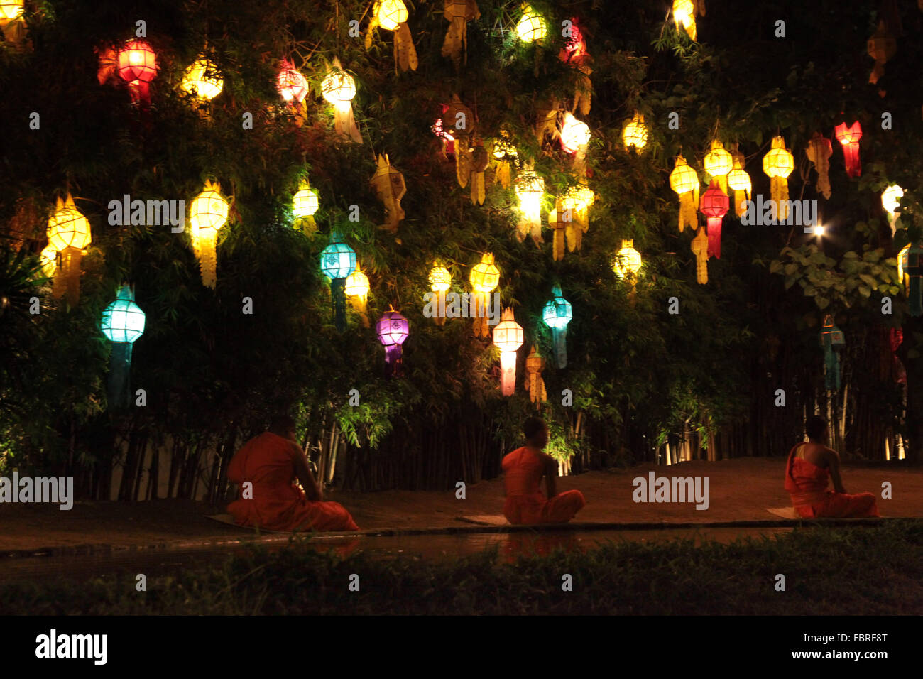 Chiang Mai, Thailand, 2016. Monks in saffron robes sitting under tree ...