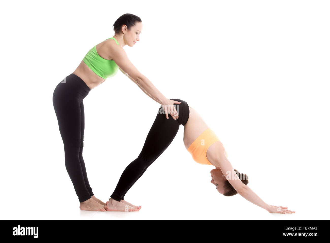 Two beautiful sporty girls practice yoga with partner, coach helps ...