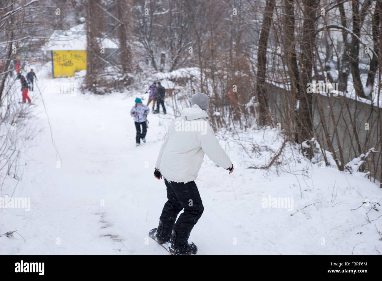 Man in white coat and gray hat behind others sliding downhill on ...