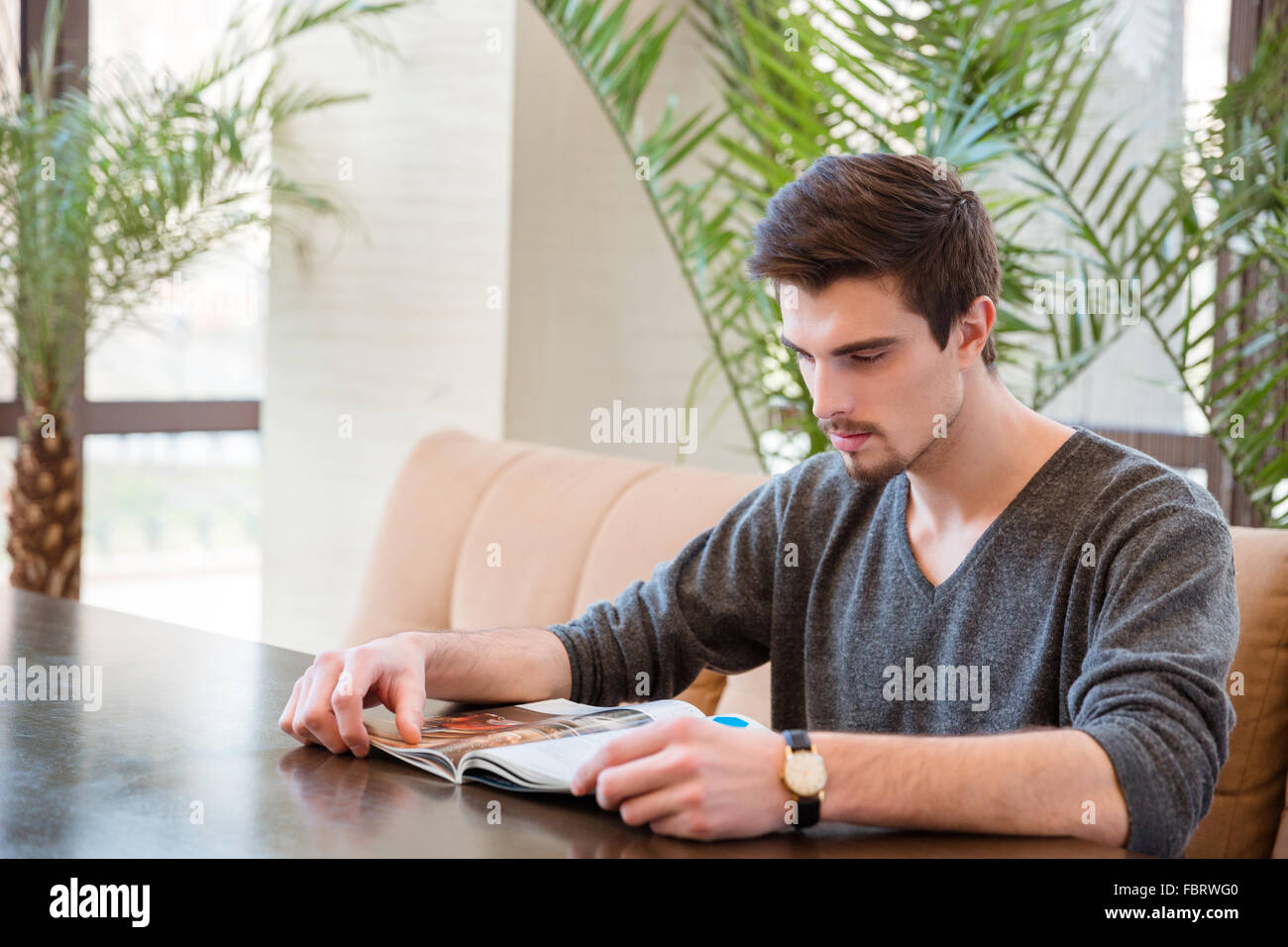 Portrait of a young man reading magazine in restaurant Stock Photo - Alamy