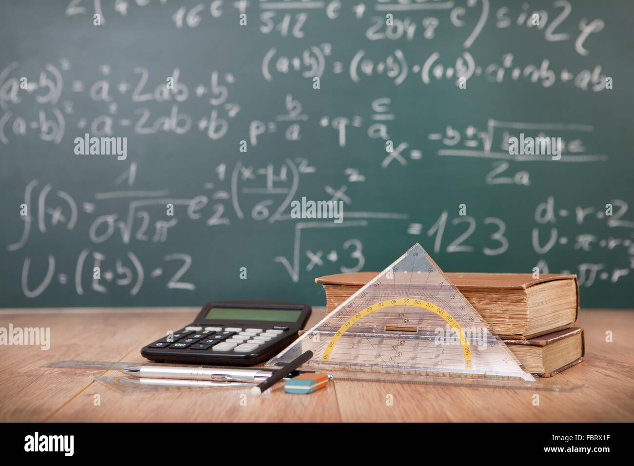 Schoolbooks and calculator lying on a wooden school desk in front of a ...