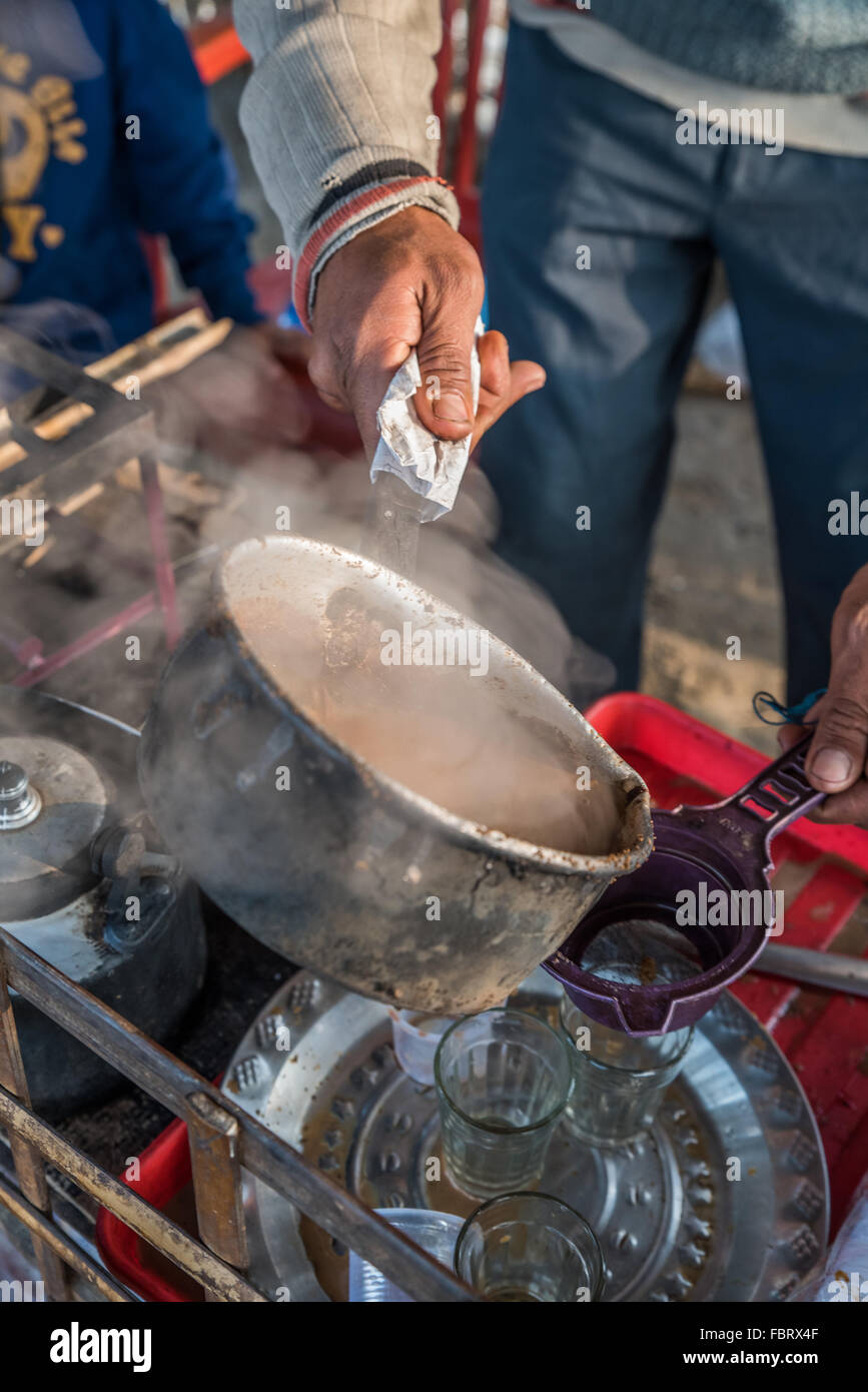 Freshly boiled and steamy chai being poured into glasses. A ...