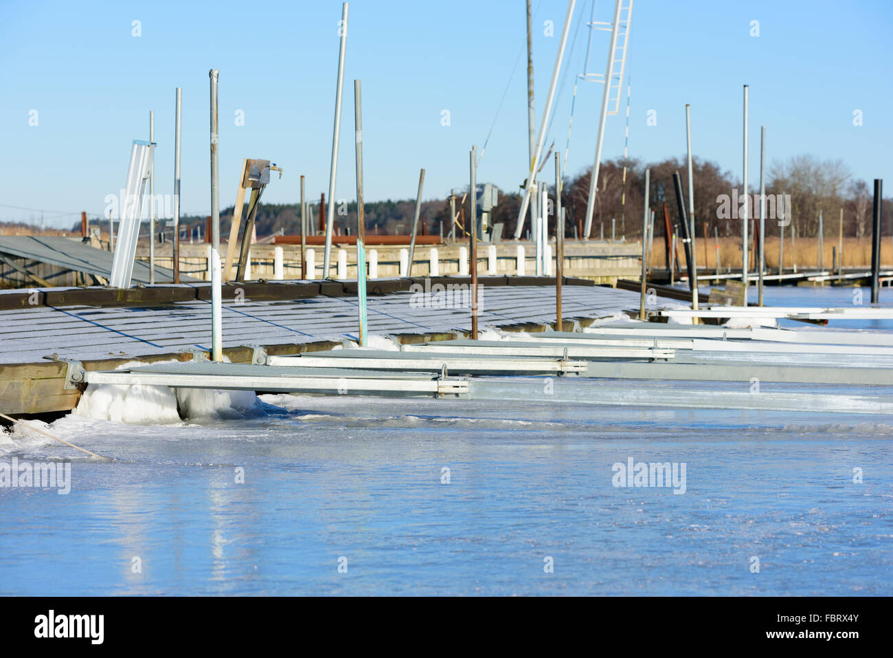 A tilting wooden floating bridge on a marina in winter. The ice has ...
