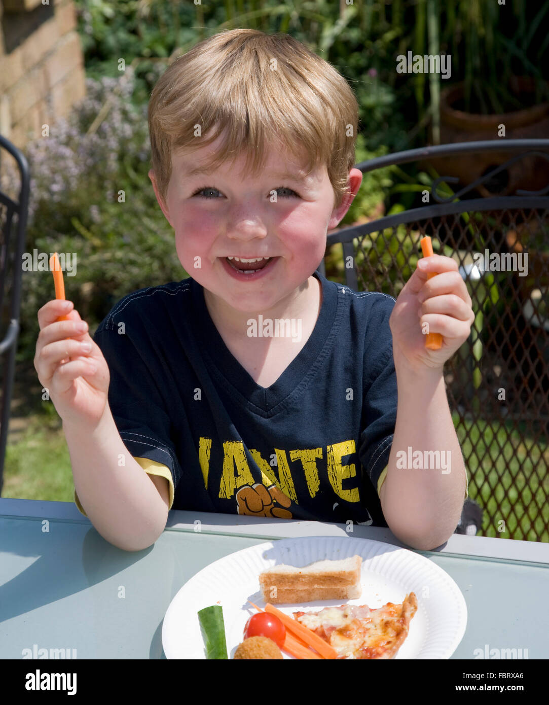 A young boy eating raw vegetables in garden picnic Stock Photo - Alamy