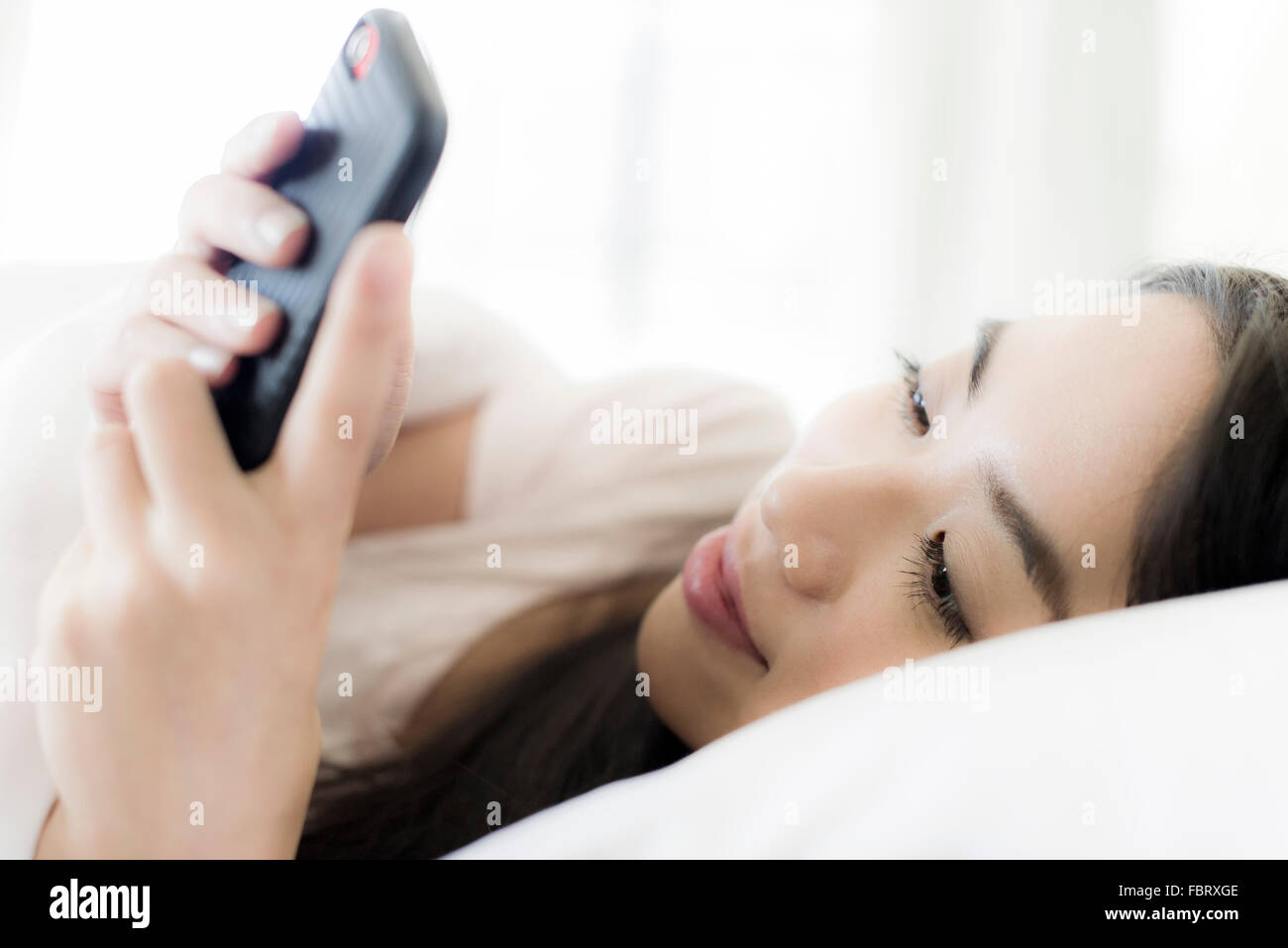 Woman lying down, using smartphone Stock Photo - Alamy
