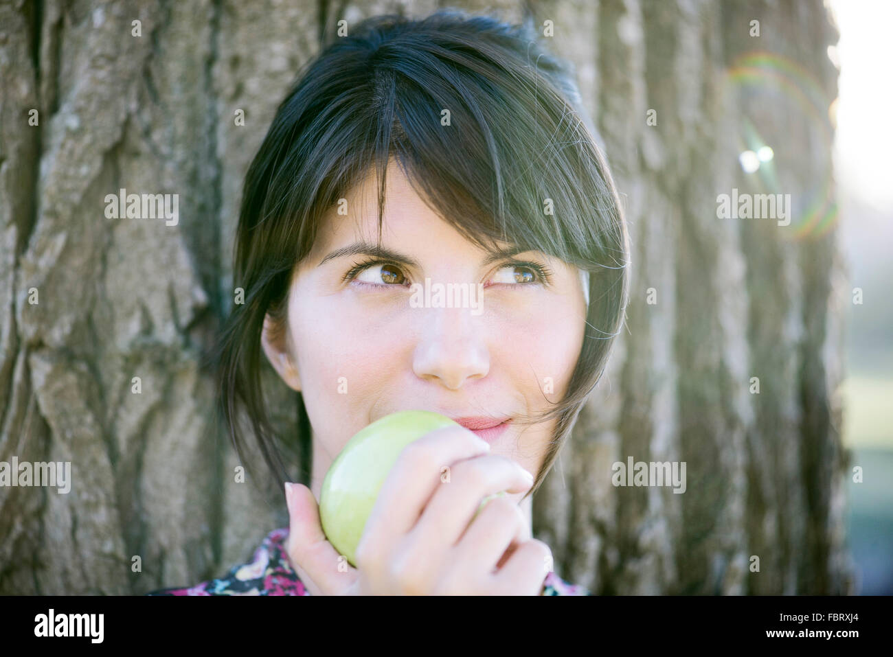 Woman eating apple, looking up thoughtfully Stock Photo - Alamy