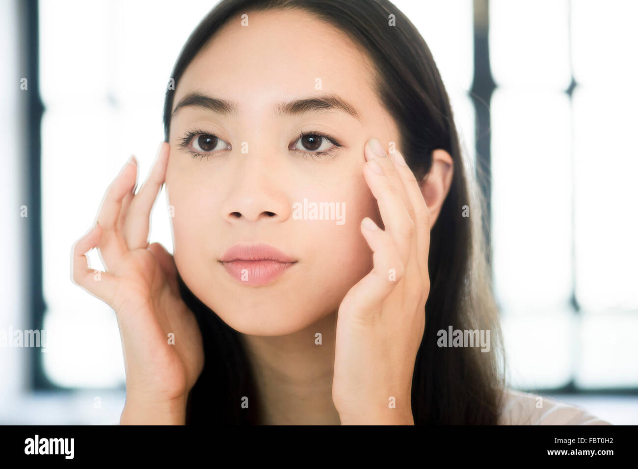 Young woman moisturising face in mirror hi-res stock photography and ...