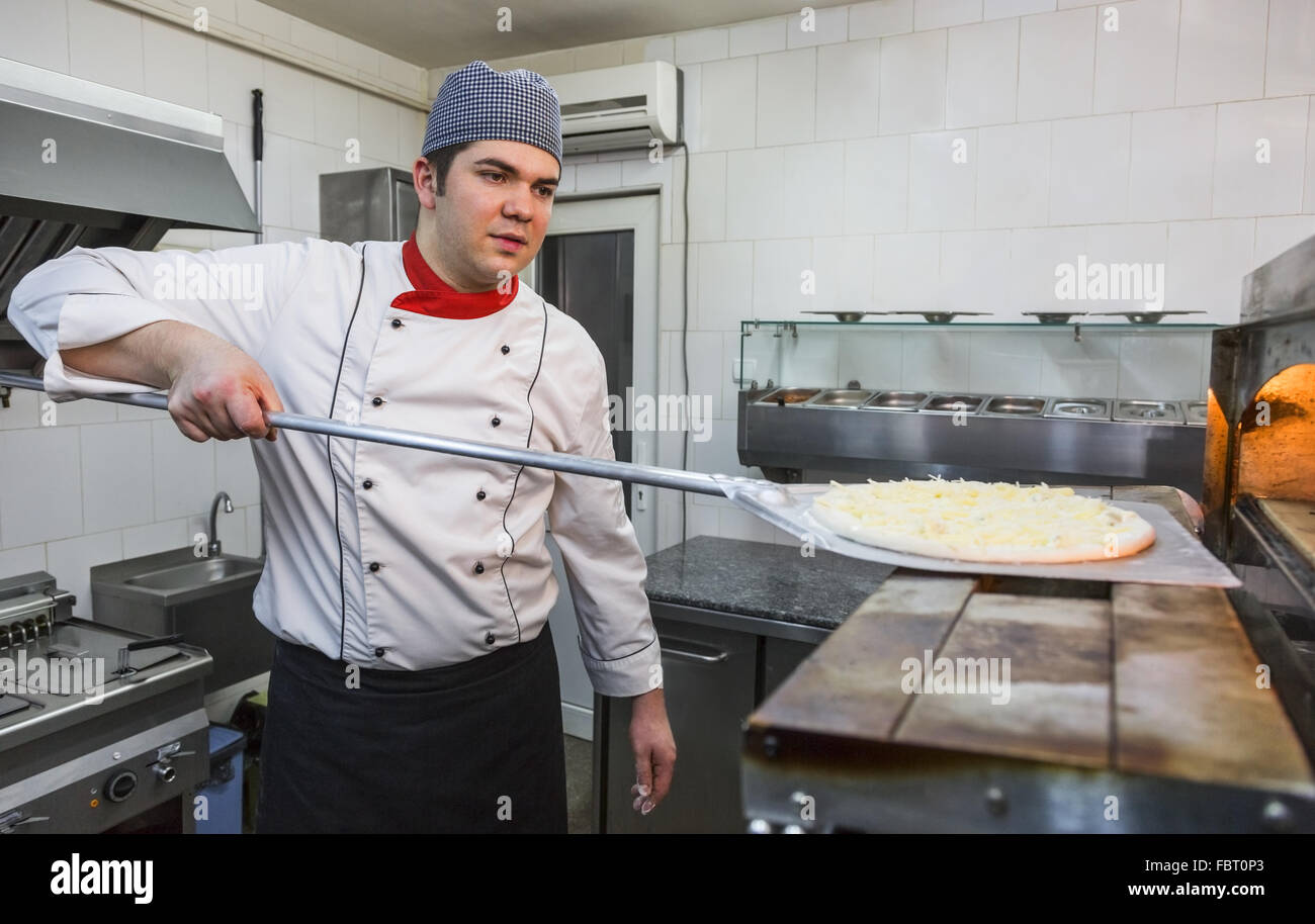 Chef introducing a pizza in a hot oven in a restaurant kitchen Stock ...