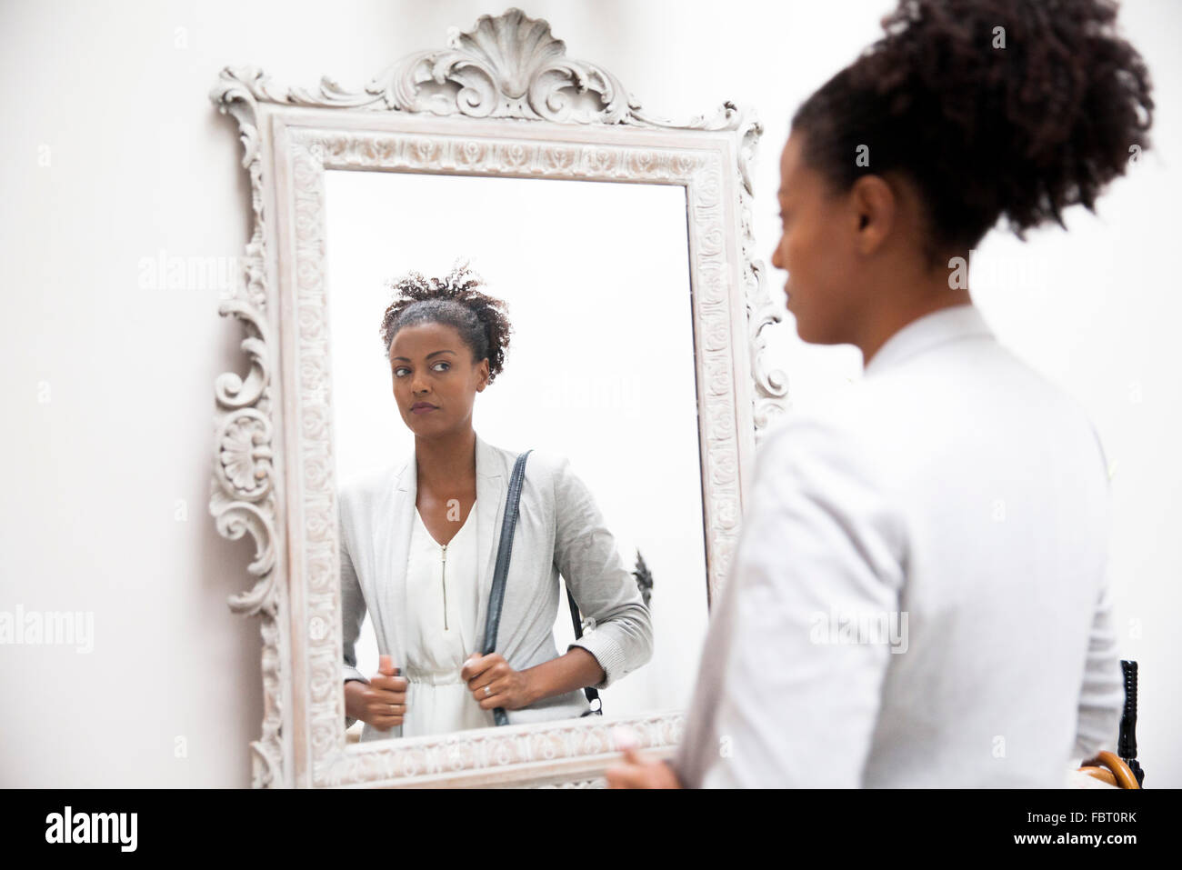 Woman looking at self in mirror Stock Photo - Alamy