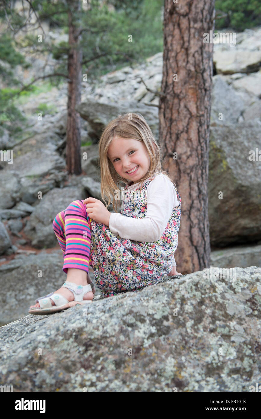 Girl sitting on rock, smiling cheerfully Stock Photo - Alamy
