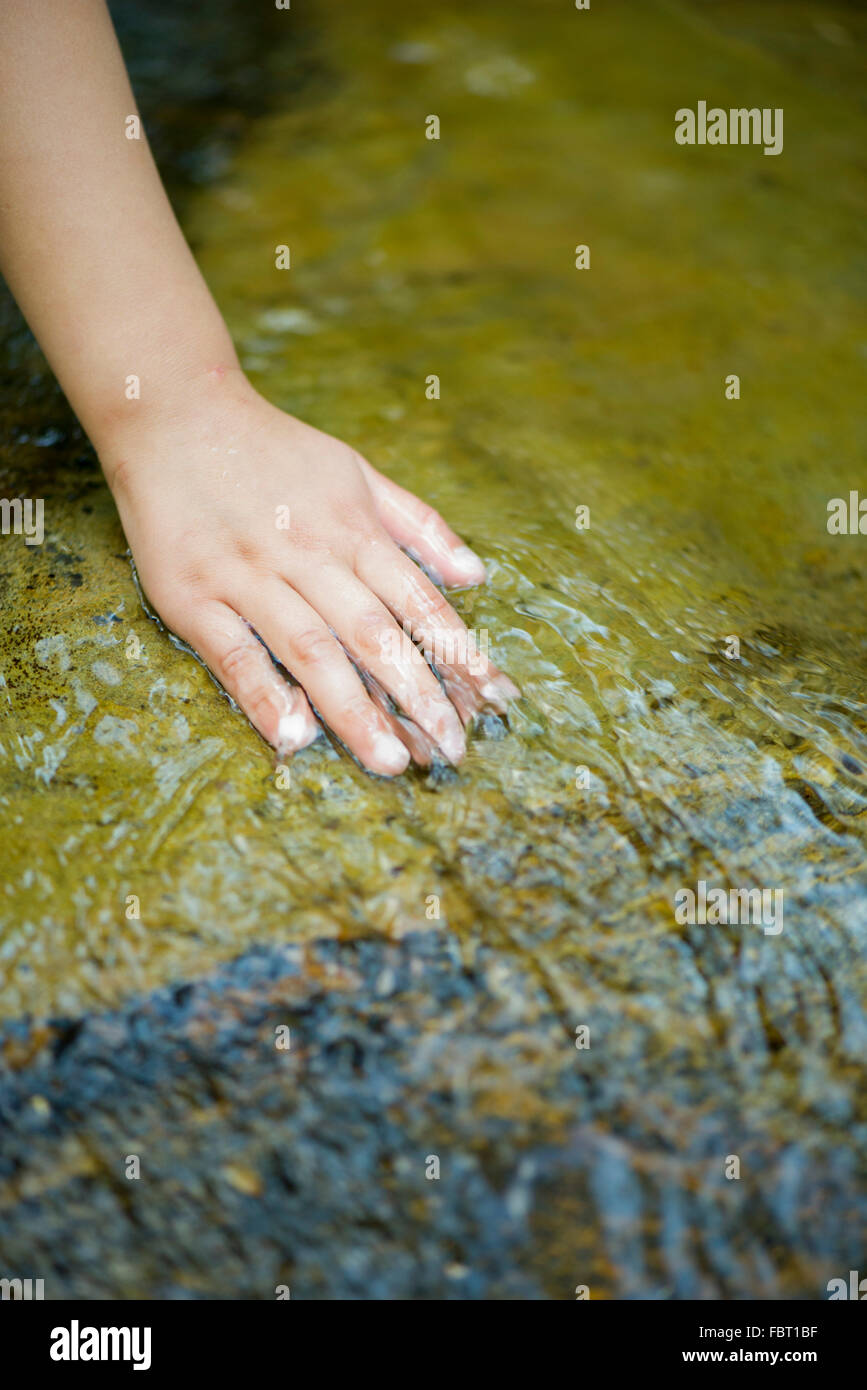 Hand touching rock in stream Stock Photo - Alamy