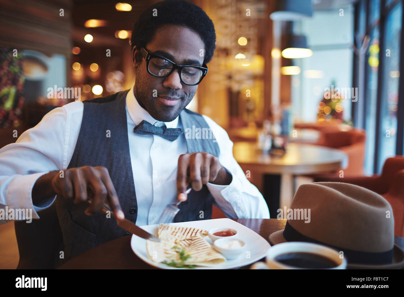 Elegant young man eating in cafe Stock Photo - Alamy