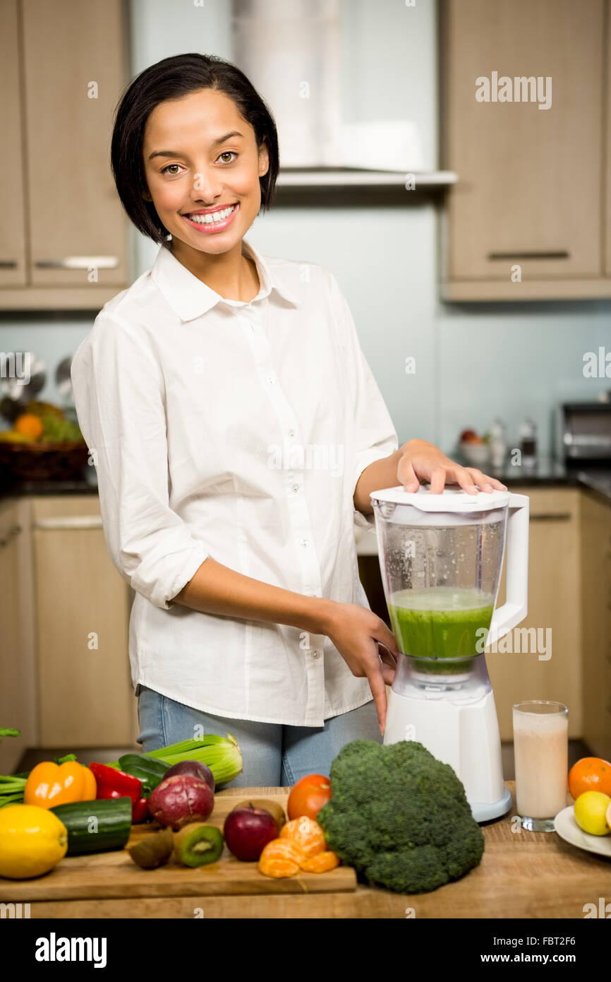 Smiling brunette preparing smoothie Stock Photo - Alamy