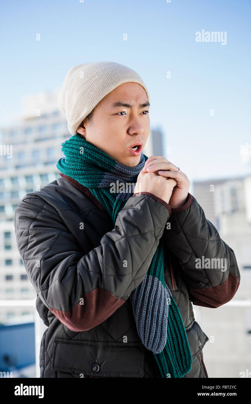Man in warm clothing blowing his hands Stock Photo - Alamy