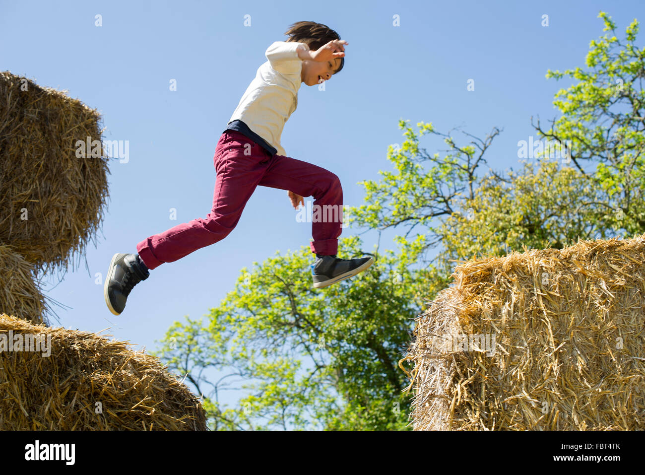 Boy jumping on haystacks Stock Photo - Alamy