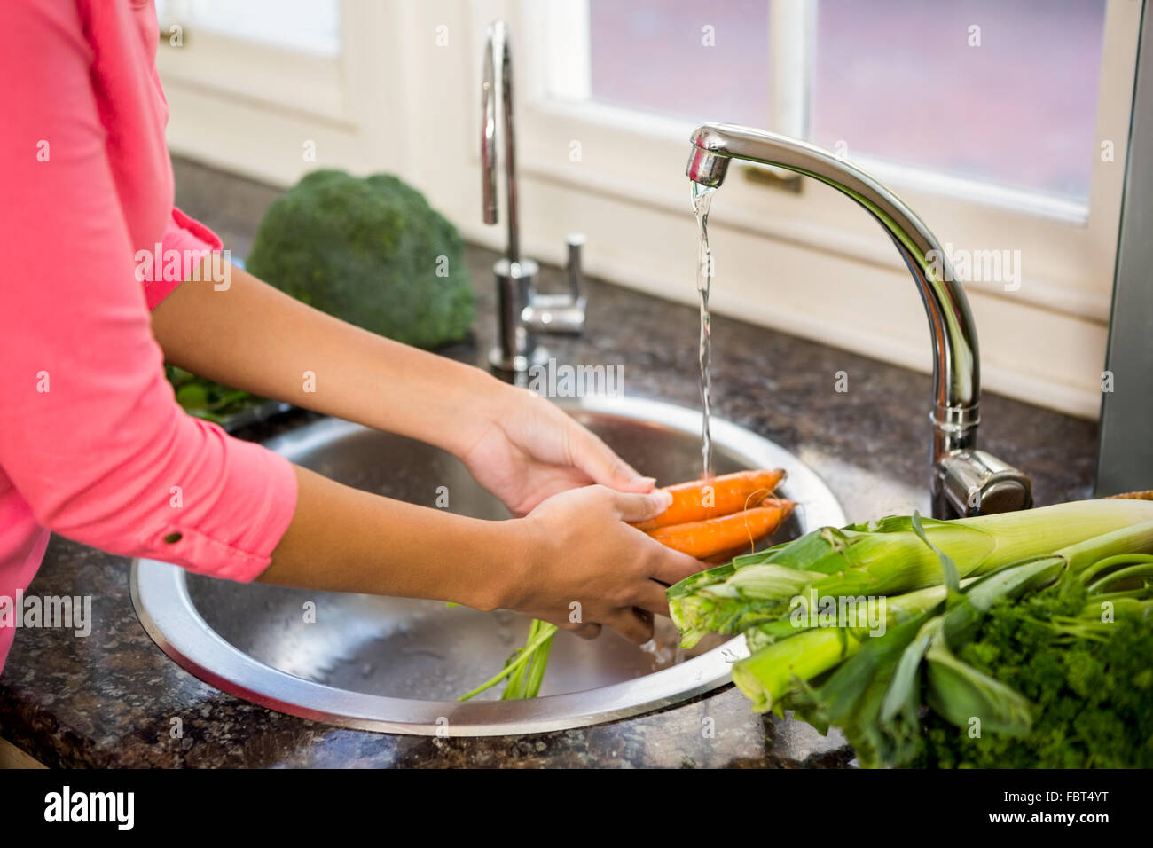 Mid section of woman washing carrots Stock Photo - Alamy