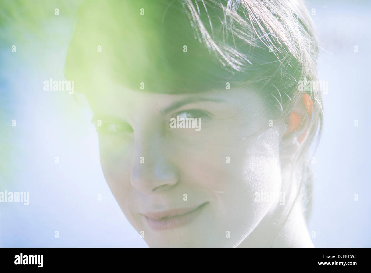 Woman smiling through foliage, portrait Stock Photo - Alamy